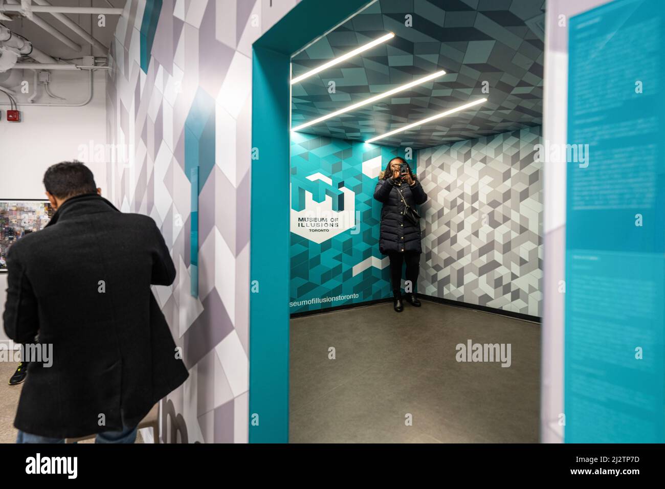 A woman seen inside of a tilted. Visitors view and experience the interactive optical illusions ...