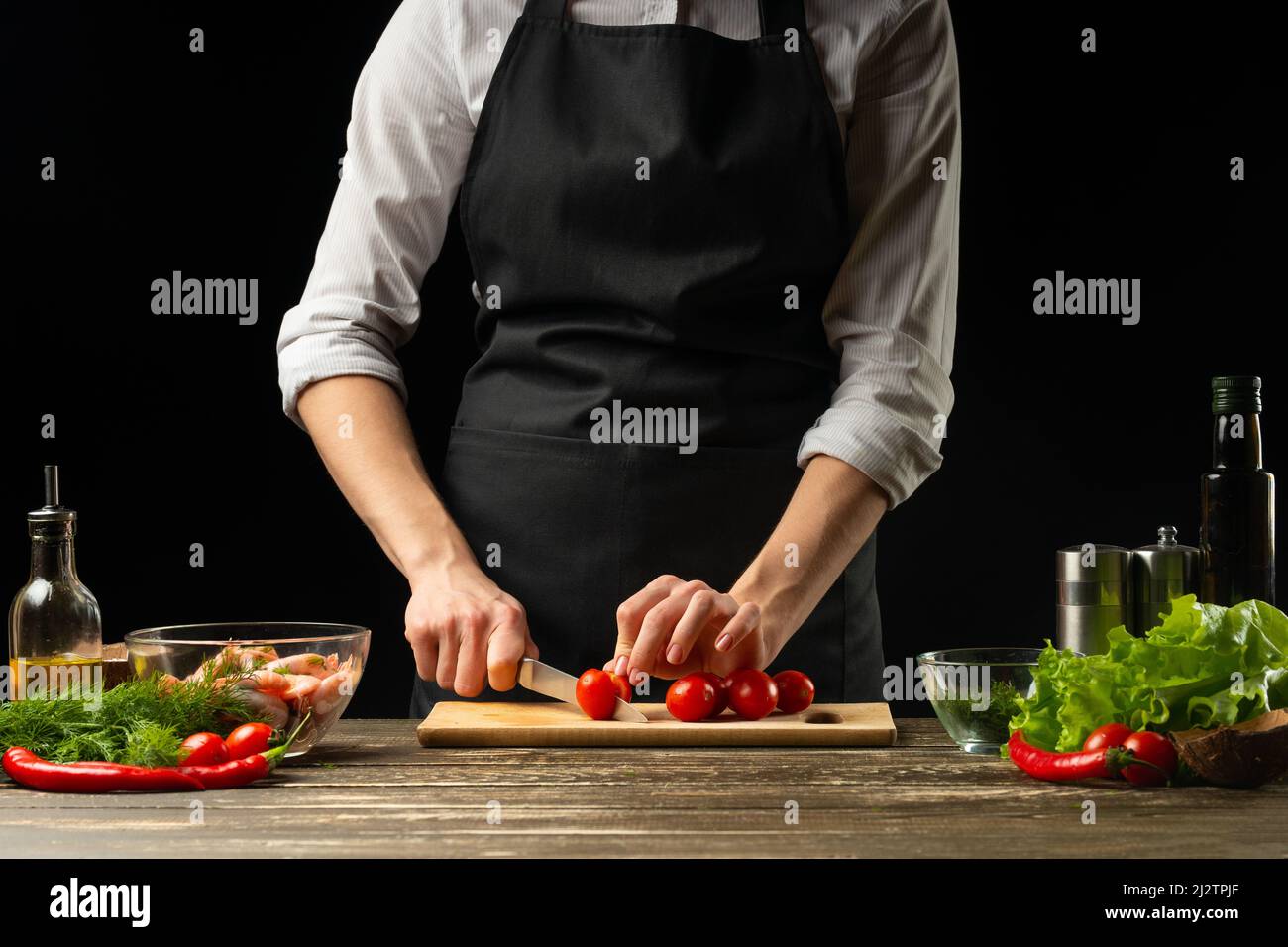 Professional chef slices cherry tomatoes for shrimp with vegetables,the ...