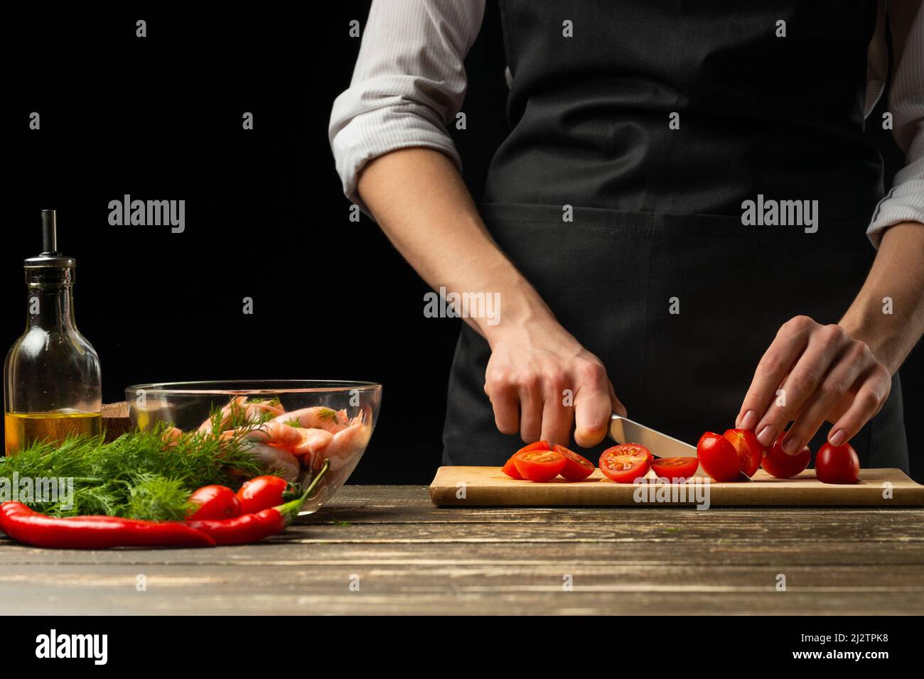 Professional chef slices cherry tomatoes for shrimp with vegetables,the ...