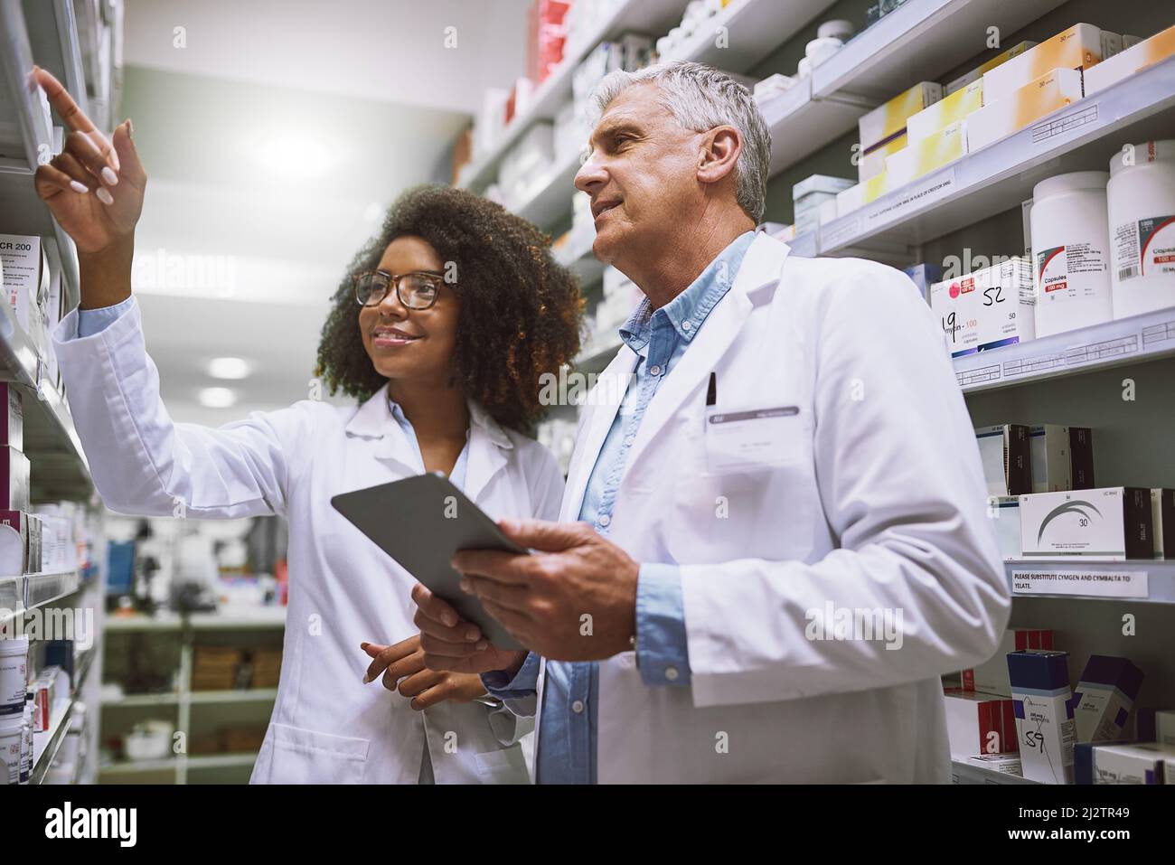 We need more of this meds. Shot of two focused pharmacist walking ...