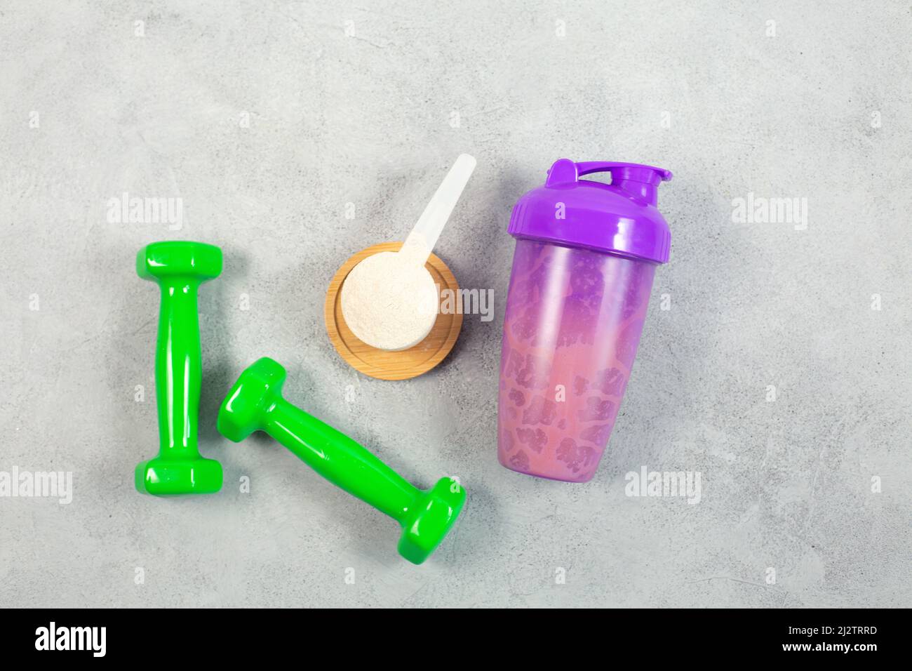 Shaker, dumbbells and Measuring scoop of protein powder on gray ...