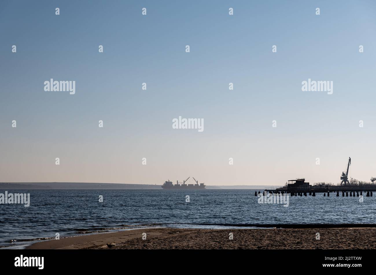 A dry cargo ship with open bilges is anchored in the middle of a wide ...
