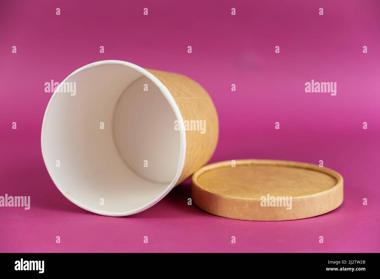 Empty cylindrical paper container with lid opposite-colored background ...