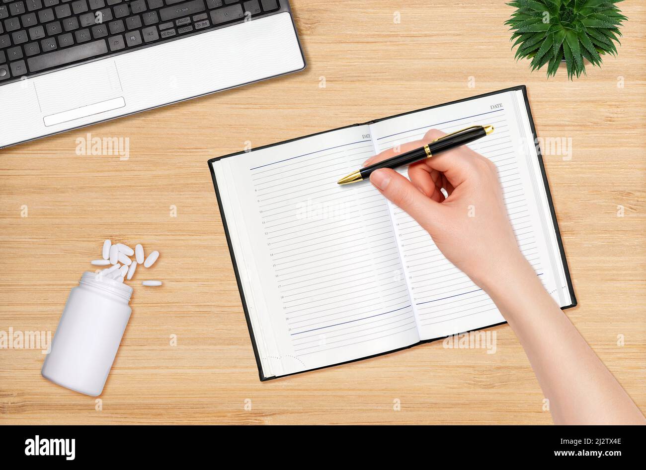 A woman's hand writes with a pen in a notebook. Next to it is a jar ...