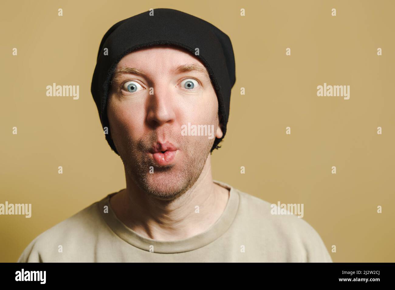 A man in a black cap looks with surprise. Portrait of a young man ...