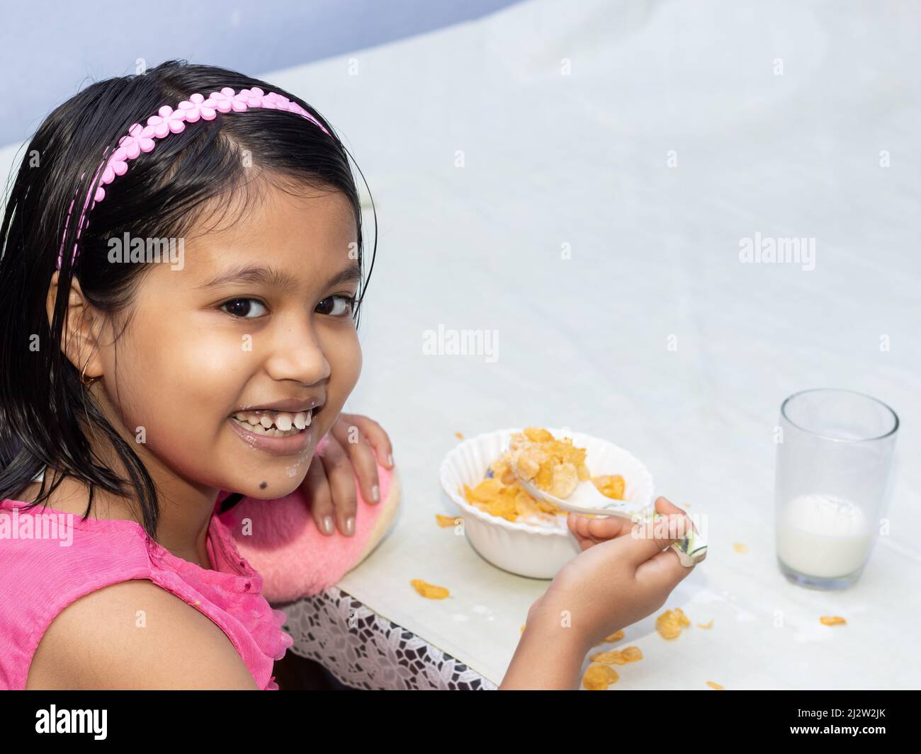 An Indian girl child eating cereal and milk with smiling face and ...