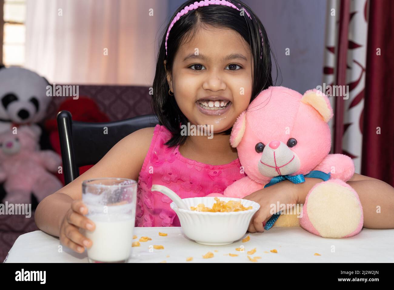 An Indian girl child eating cereal with milk with smiling face and ...