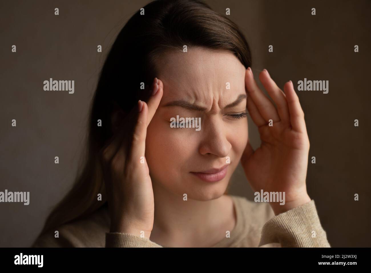 Portrait of a beautiful young girl touching her temples, feeling stress ...