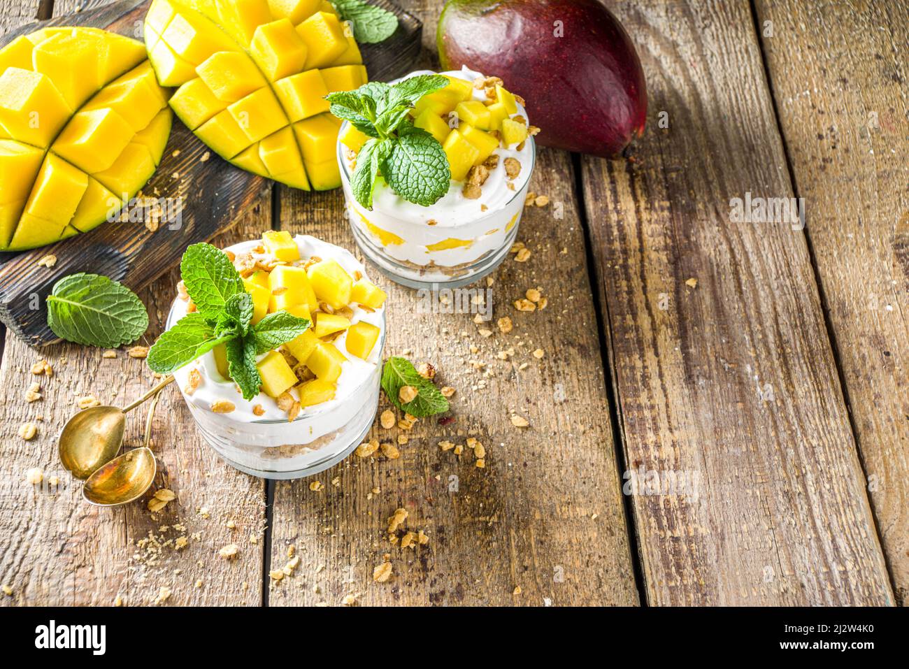 Summer breakfast layered dessert with mango and granola. Mango parfaits ...