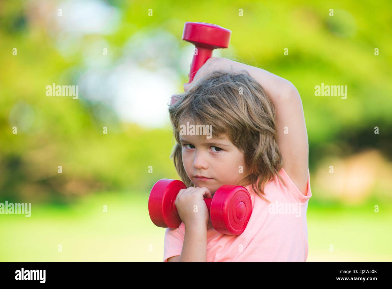 Sport child boy with strong biceps muscles. Kids exercising fitness dumbbells. Strong little boy ...