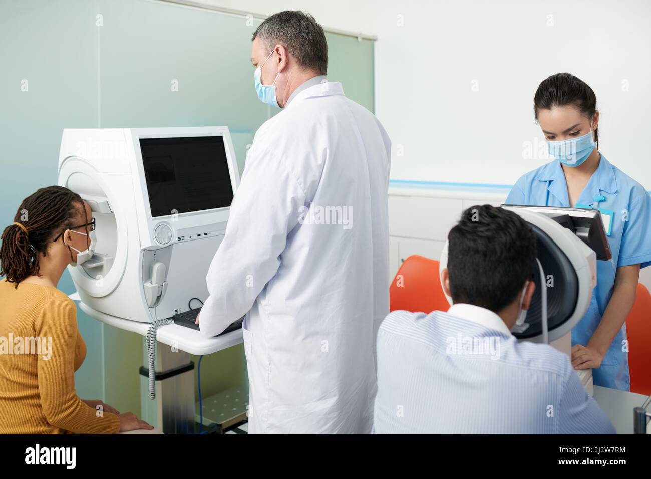 Optometrist and nurse using modern equipment to diagnose and identify ...