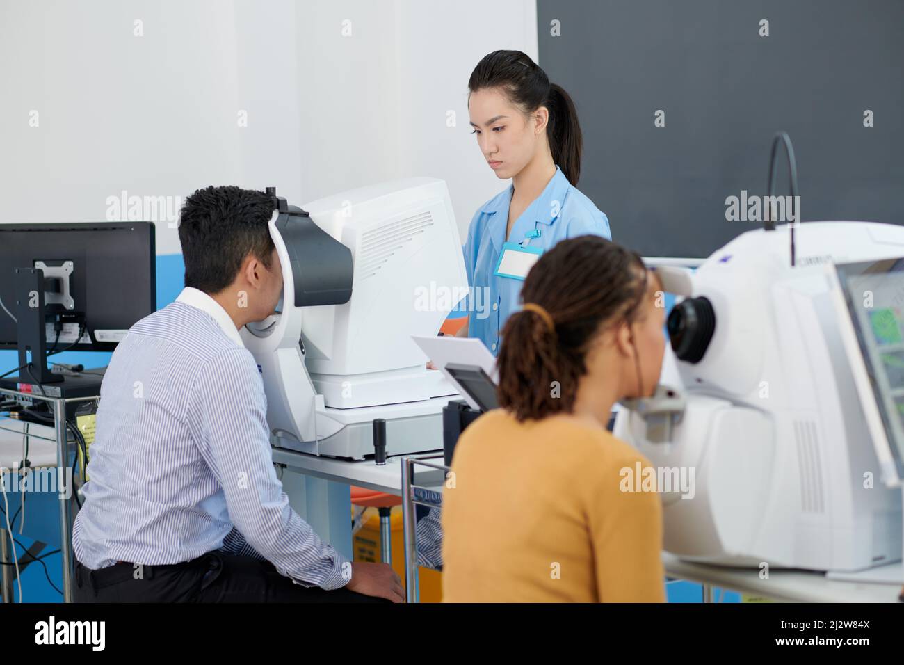 Concentrated young ophthalmic nurse setting modern equipment to test ...