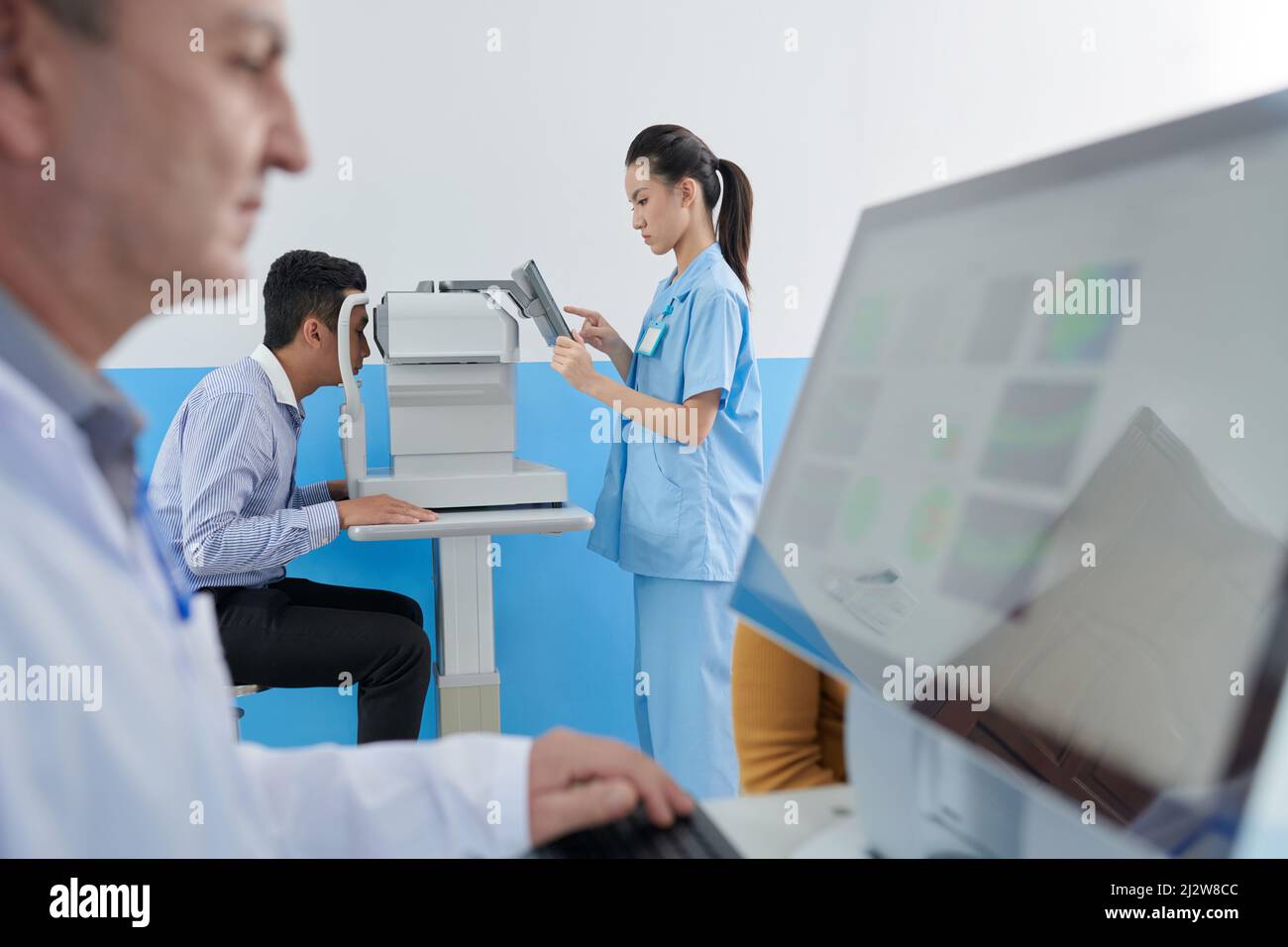 Ophthalmic nurse using modern equipment for diagnosting eye disease of ...