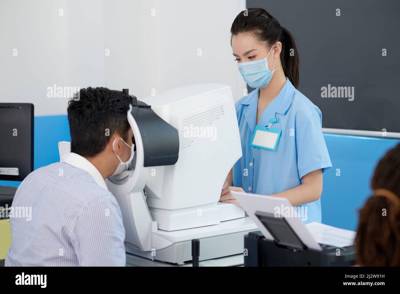 Patient getting eyes checked with refractometer to get prescription for ...