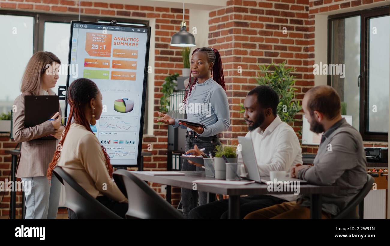 Multi ethnic colleagues presenting analysis charts on display, planning ...