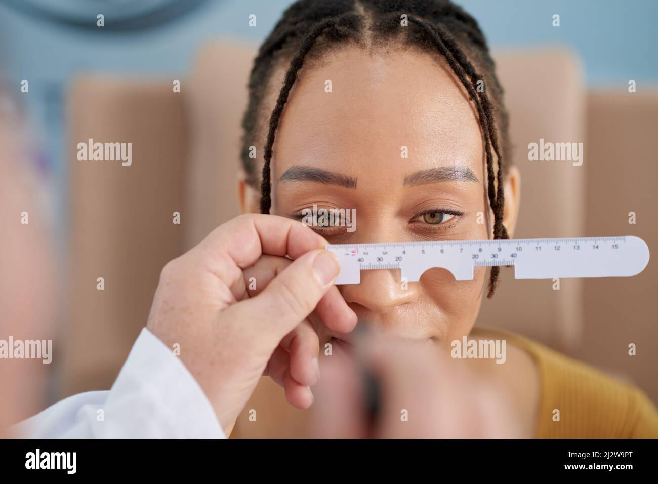 Ophthalmologist measuring distance between eyes of female patient with ...