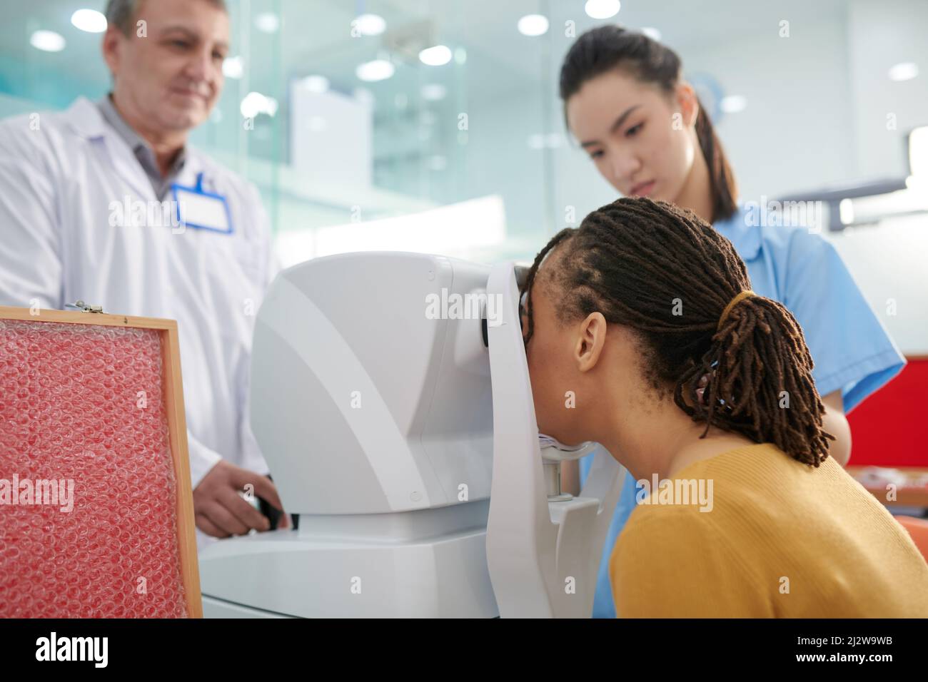 Female patient putting head in autorefractor when doctor and medical ...