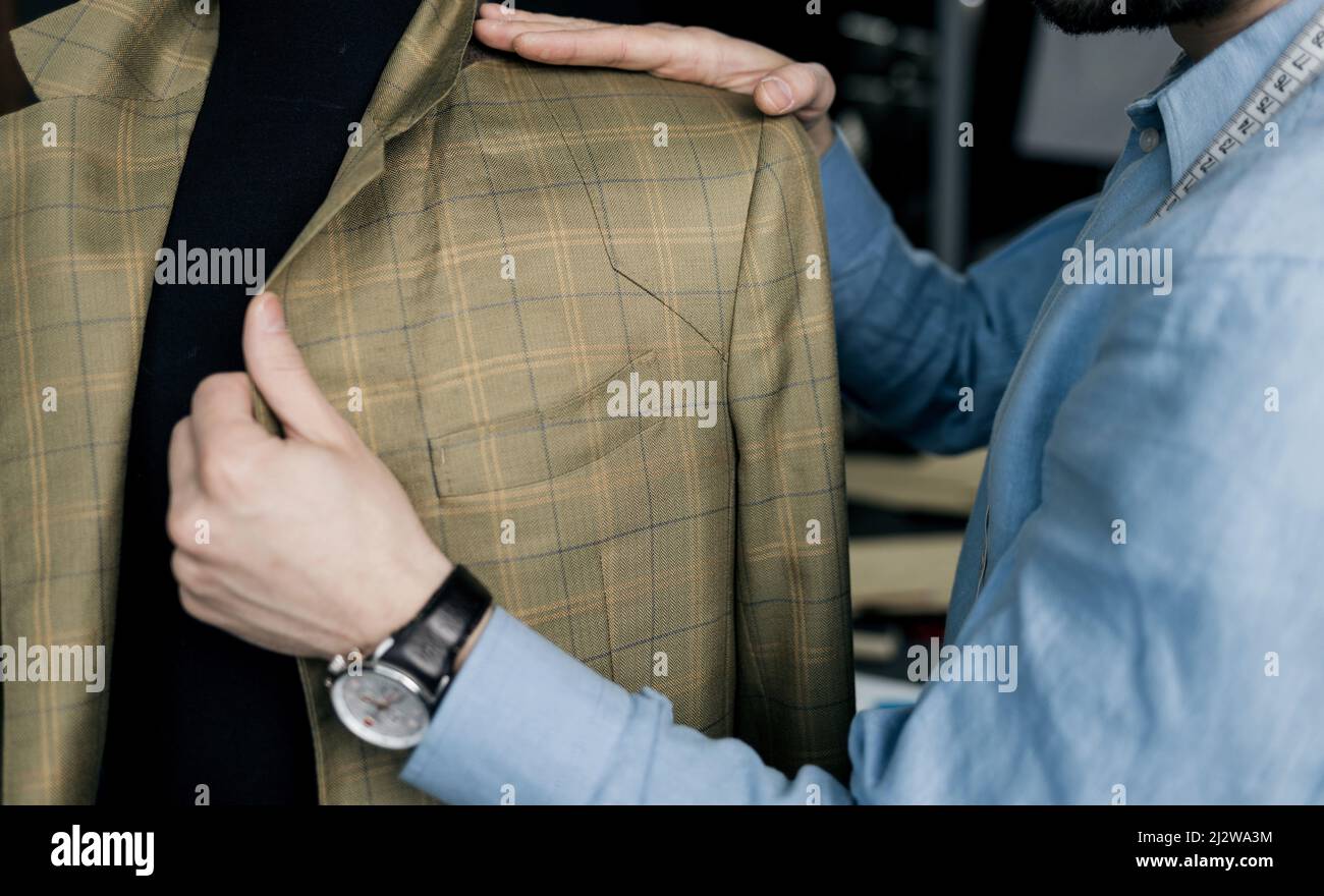 male tailor prepares a suit for showing to a client. individual ...