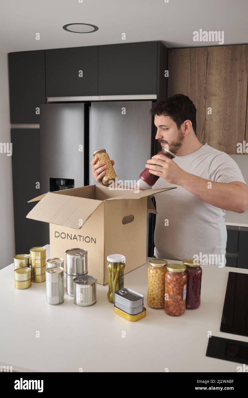 Young latin man filling donation box with non-perishable food Stock ...