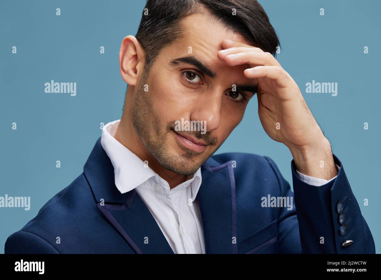 a man in a blue business suit close-up face holds his hand near his ...