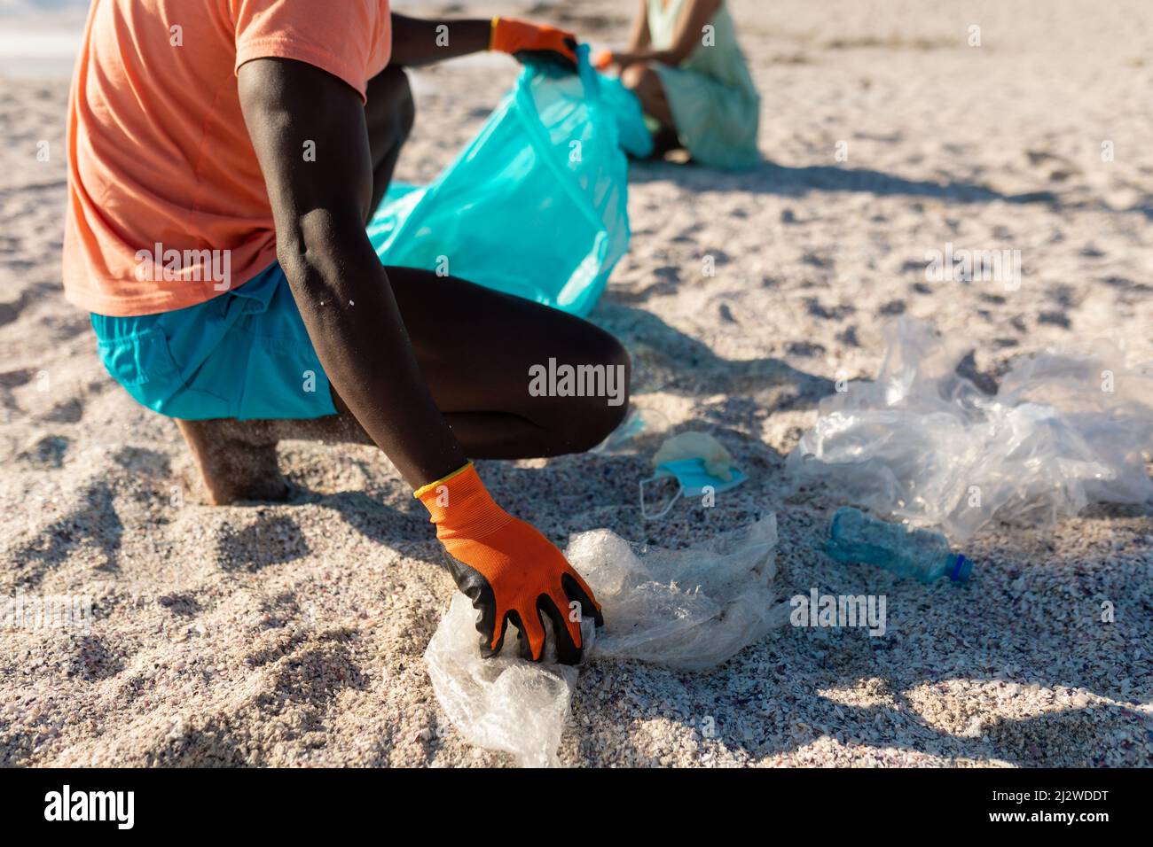 Low section of african american man collecting garbage in plastic bag ...