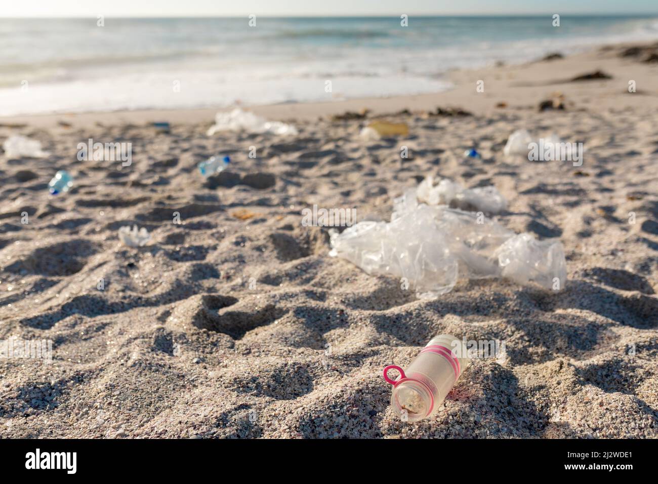 Plastic waste scattered on sand at beach during sunny day Stock Photo ...