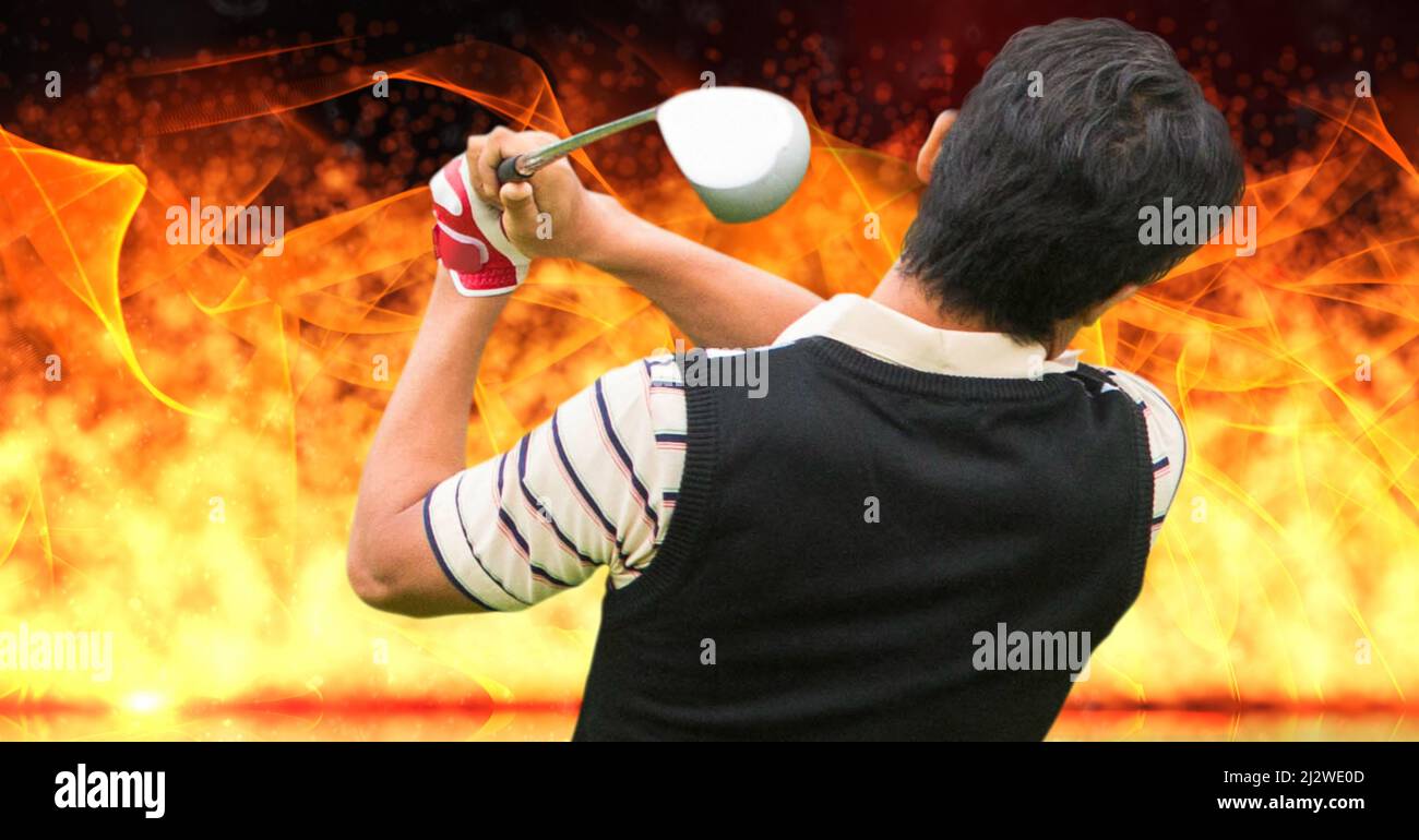 Rear view of asian male golf player swinging golf club against fire ...