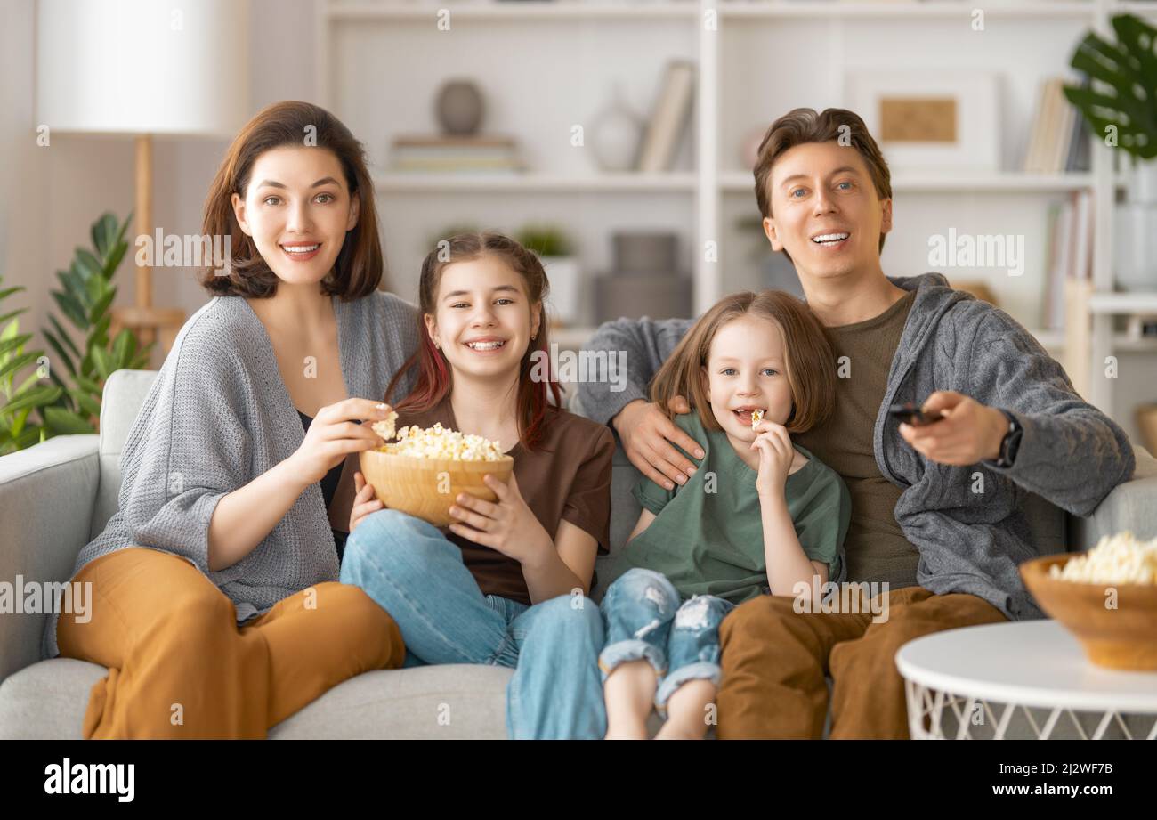 Happy family watching projector, TV, movies with popcorn in the evening ...