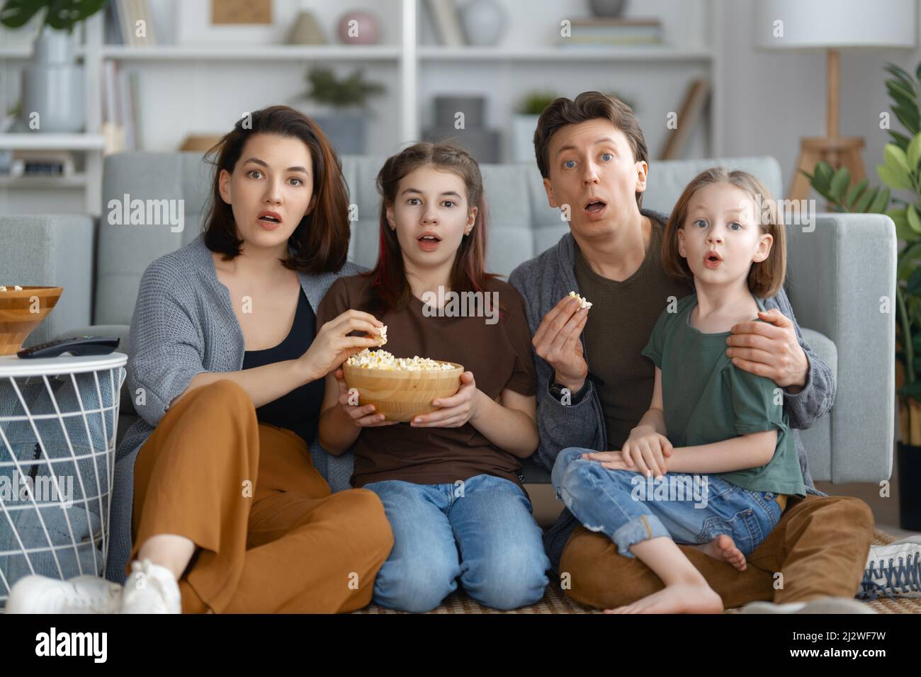 Family watching projector, TV, movies with popcorn in the evening at ...