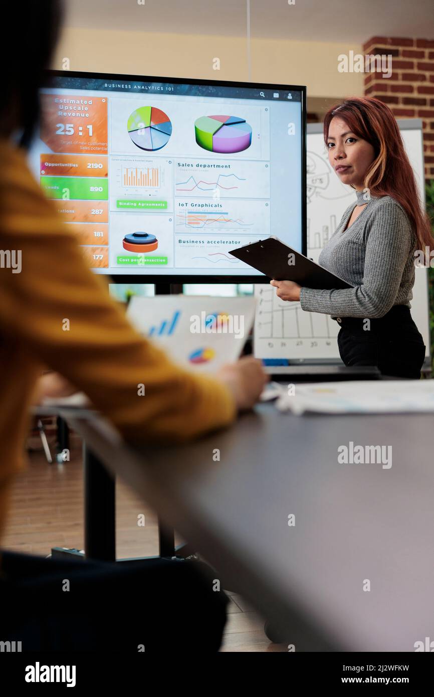 Businesswoman Explaining Management Statistics To Asian Manager Working