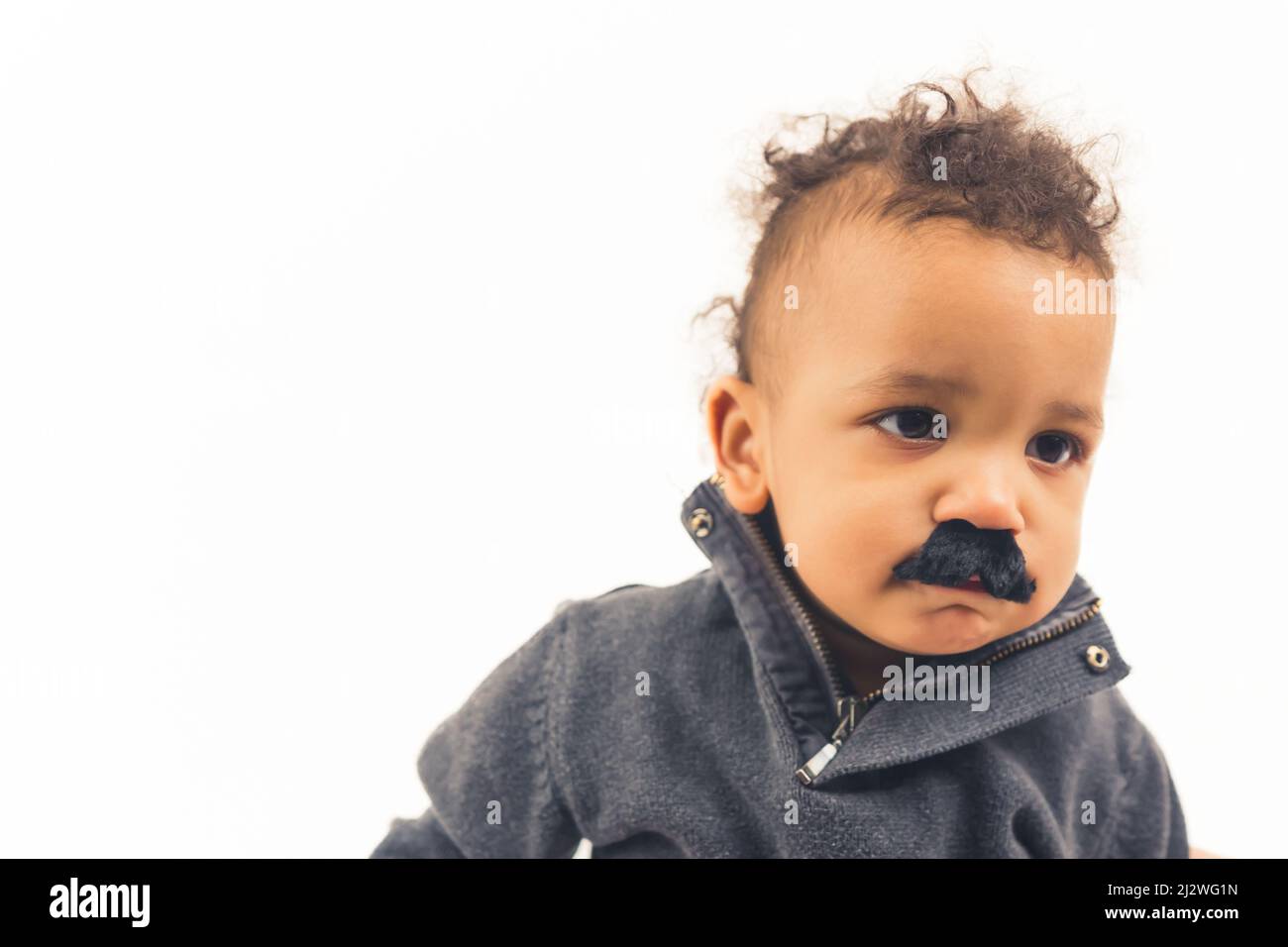 Grumpy stuffy multiracial baby boy in black fake moustache over white ...