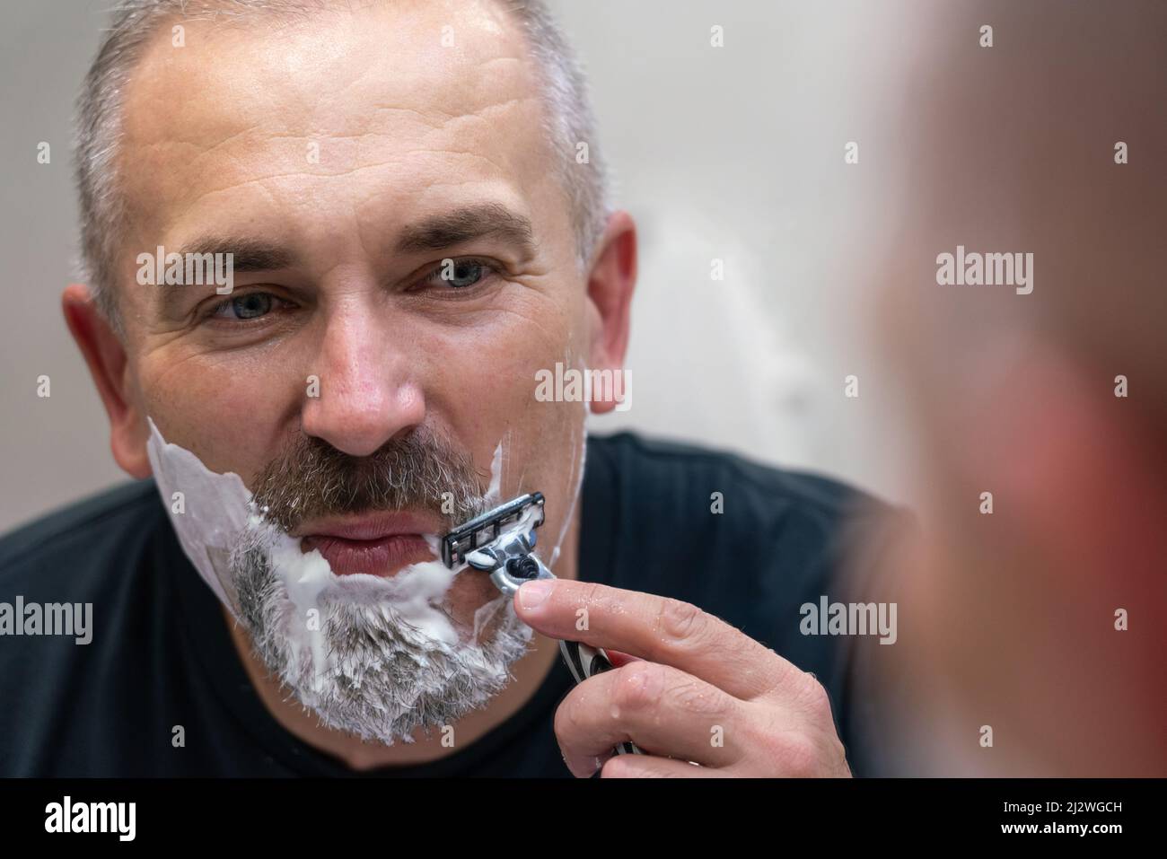 Middle aged handsome man shaving his beard in bathroom Stock Photo - Alamy