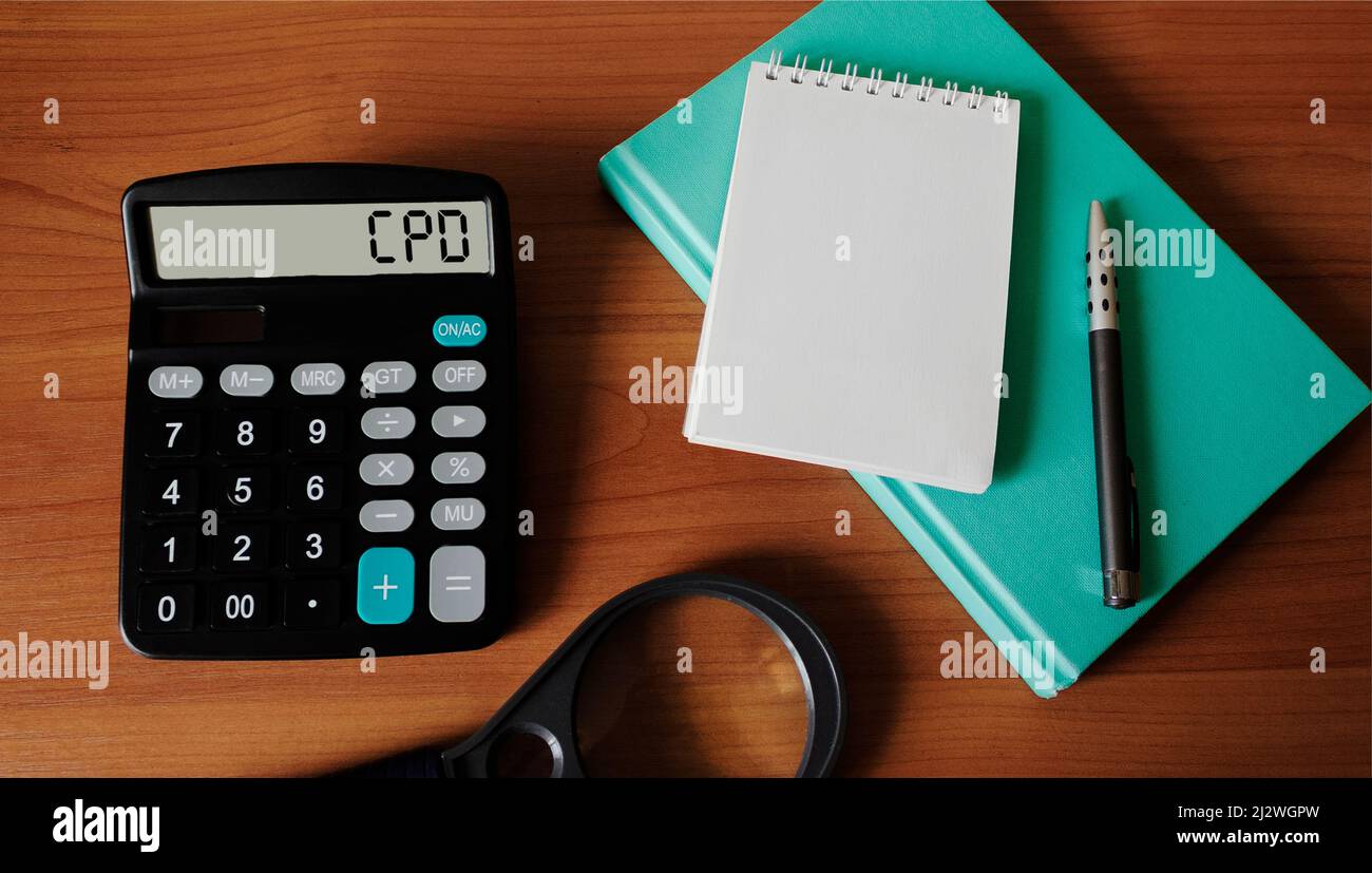 Calculator with CPD text on wooden background with notepad to write ...