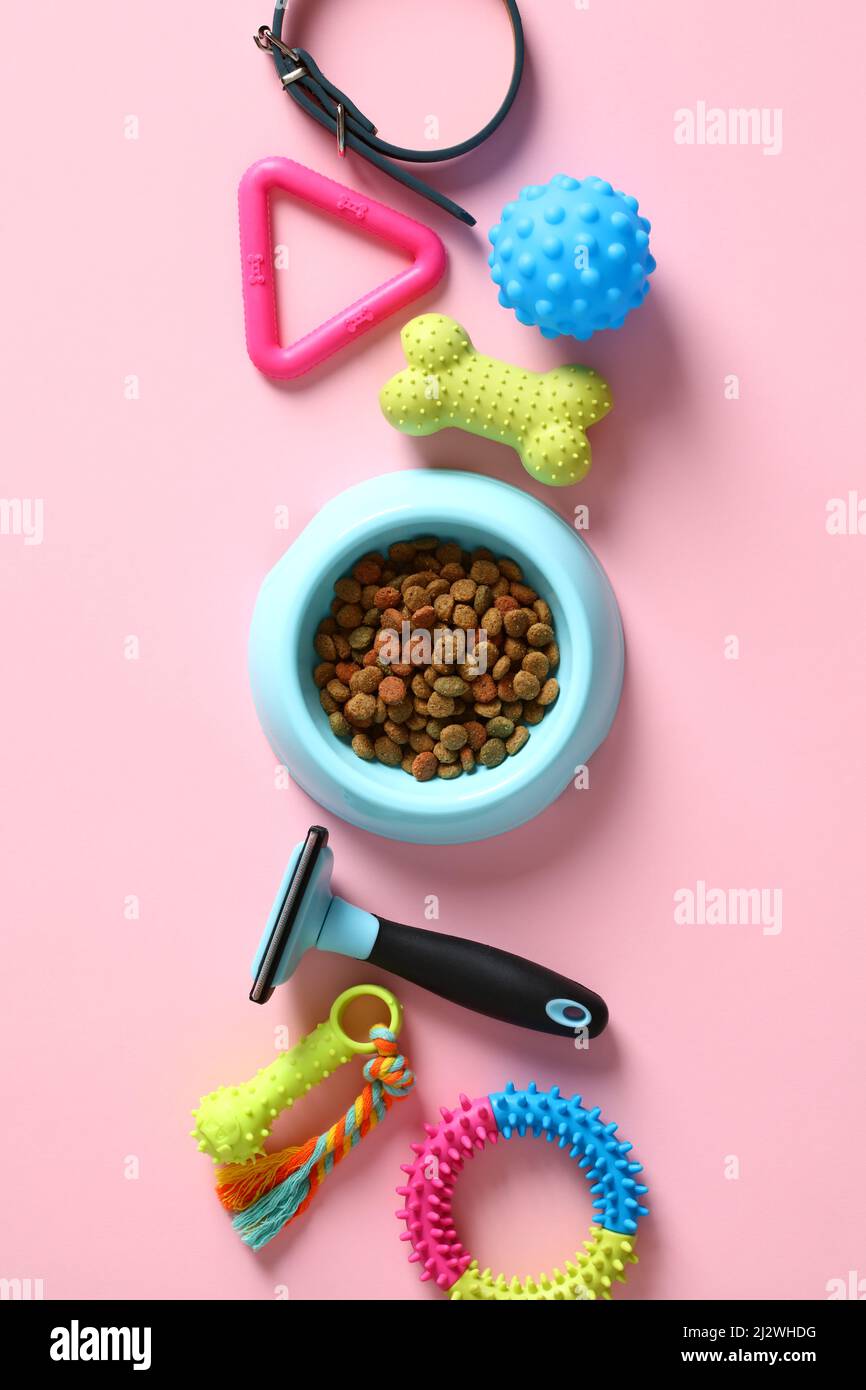 Flat lay composition with bowl of dry feed and pet accessories on pink ...