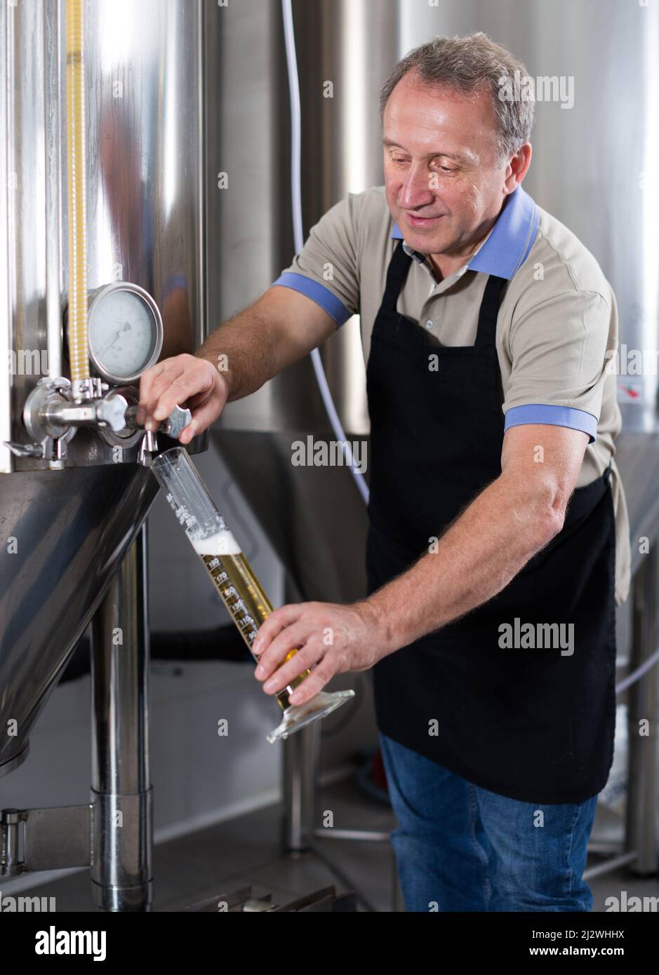 Adult brewer is standing with flask for beer Stock Photo - Alamy