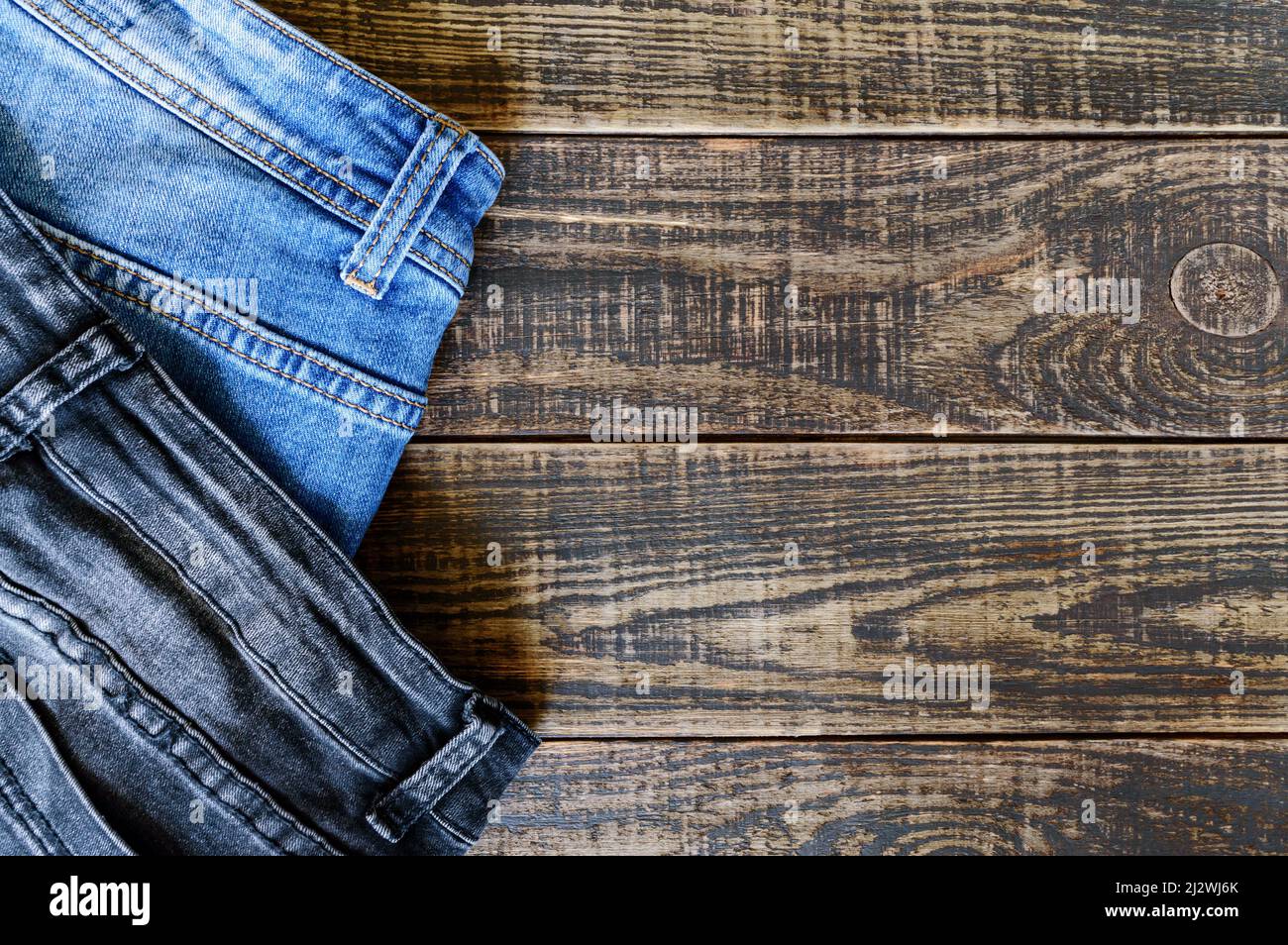 Blue and black jeans trousers on a rustic wooden background with copy ...