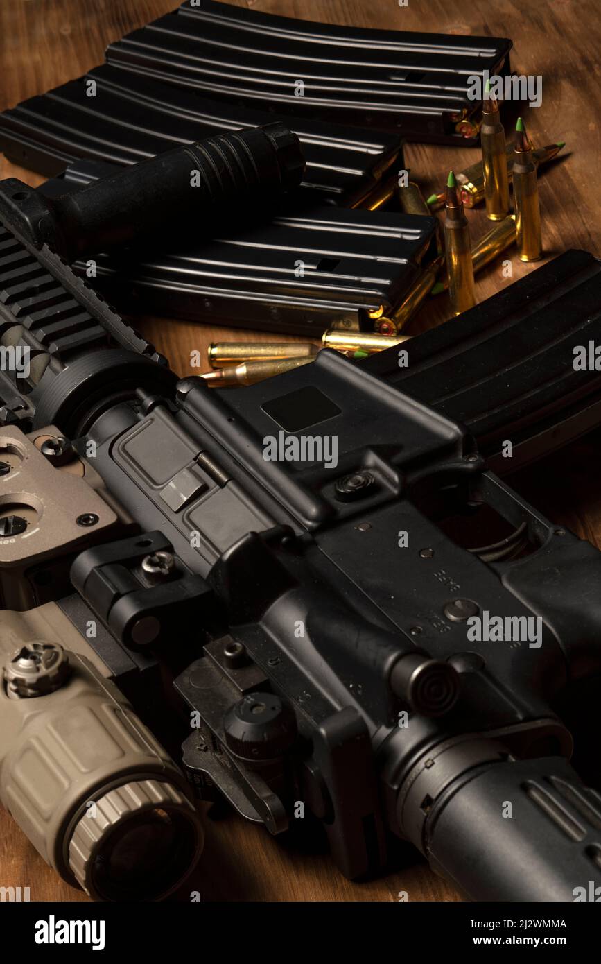 m4 rifle with optical sight, ammunition and cartriges on wooden table ...