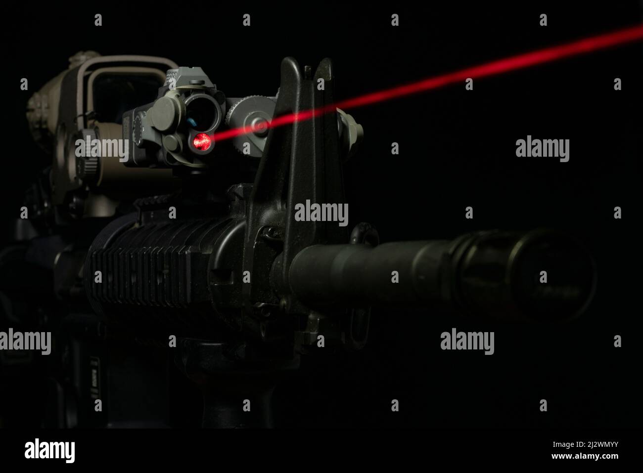 Optical sight and laser device with a red beam on the M4 rifle on dark ...