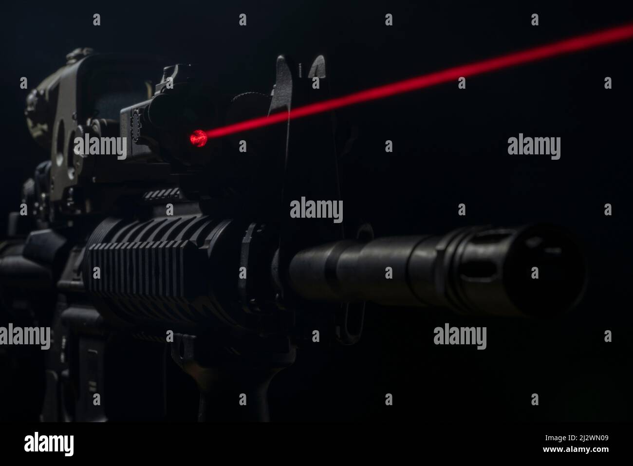 Optical sight and laser device with a red beam on the M4 rifle on dark ...