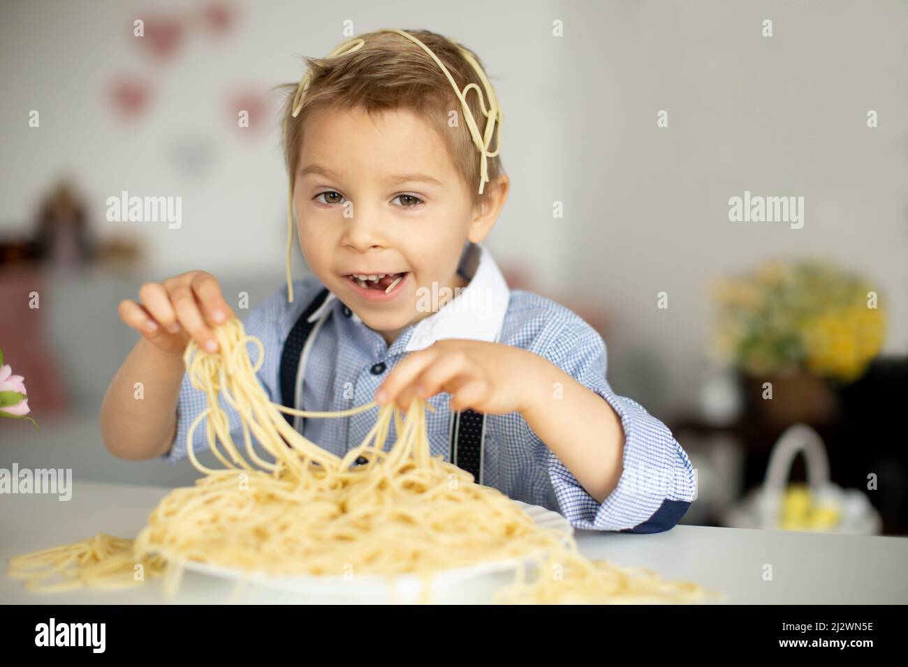 Cute preschool child, blond boy, eating spaghetti at home, making a ...