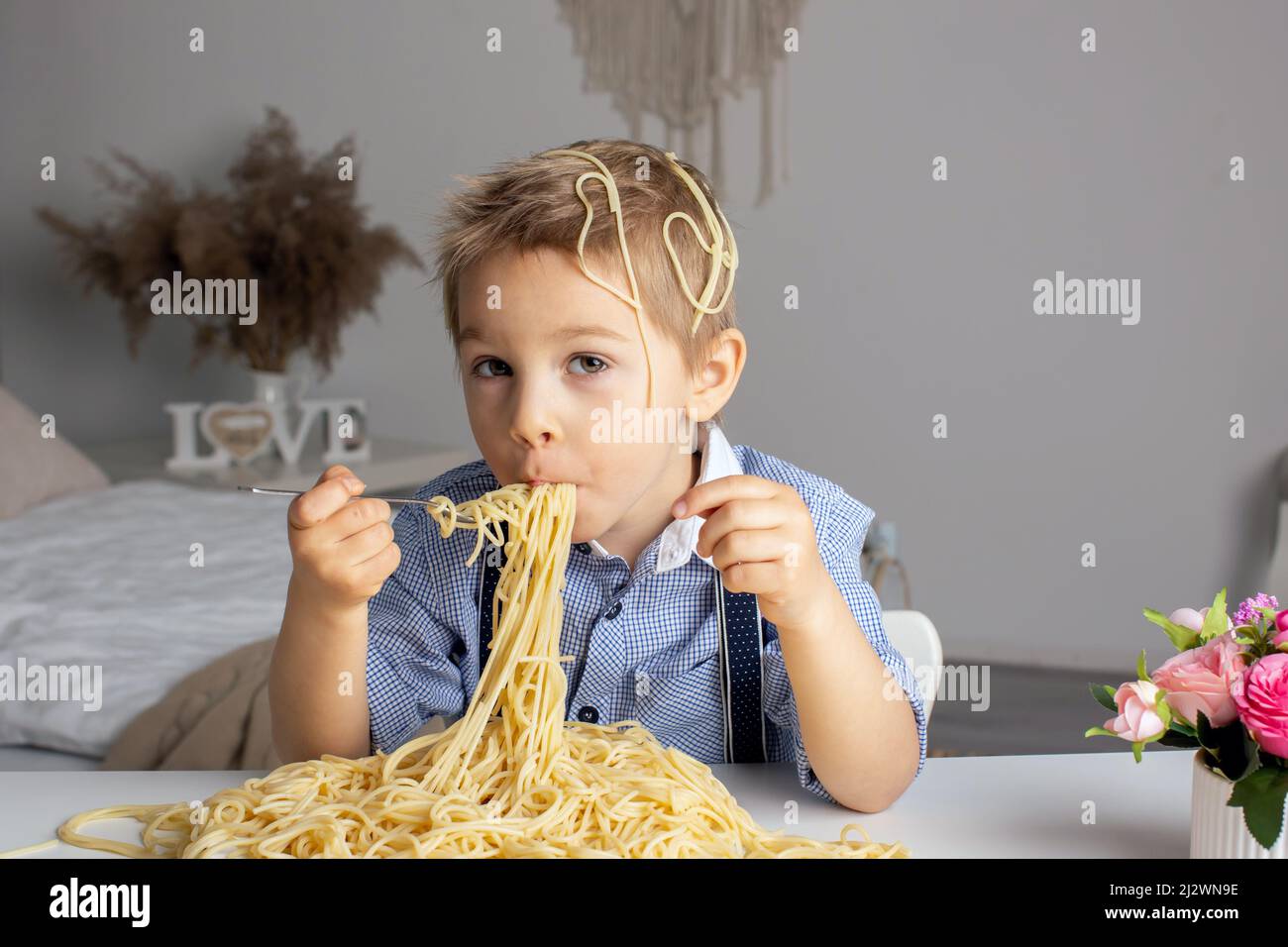 Cute preschool child, blond boy, eating spaghetti at home, making a ...