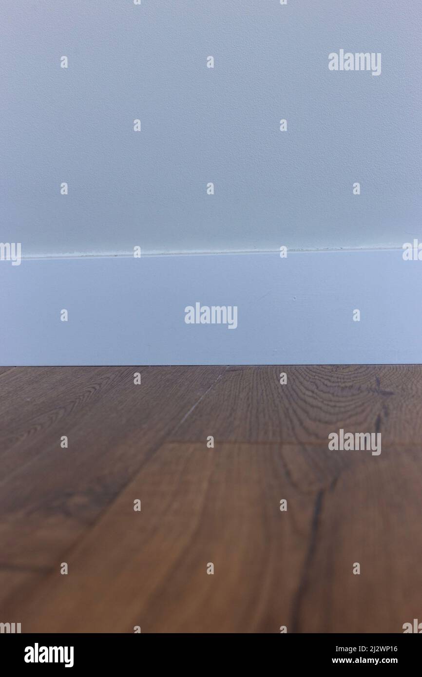 White baseboard, white wall and wood laminate Stock Photo - Alamy