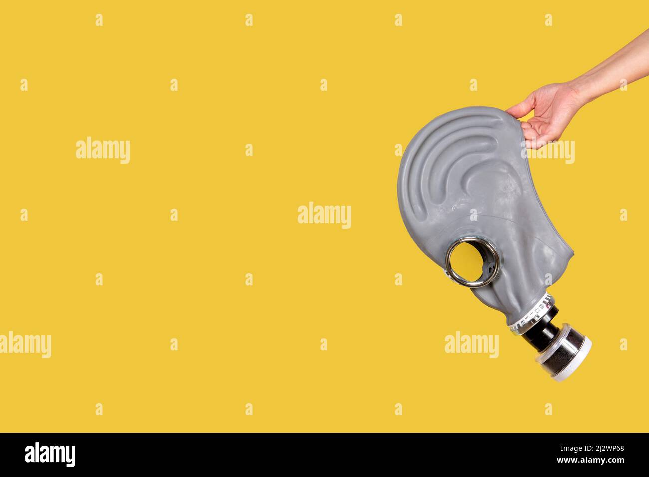 Hand holding gas mask on yellow background Stock Photo - Alamy