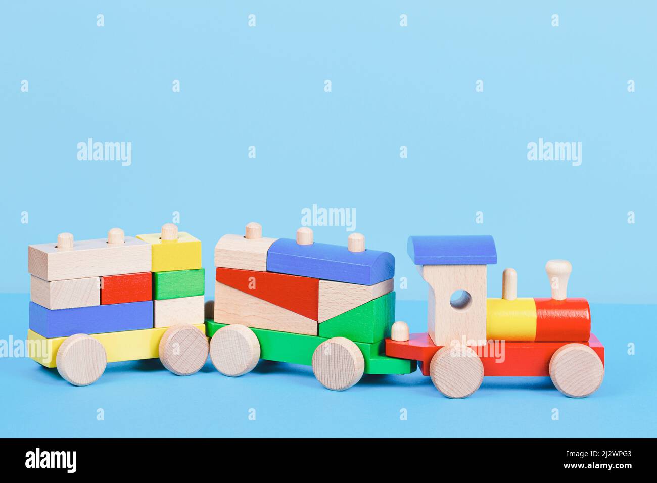 Wooden toy train with colorful blocks ion light blue background. Front ...