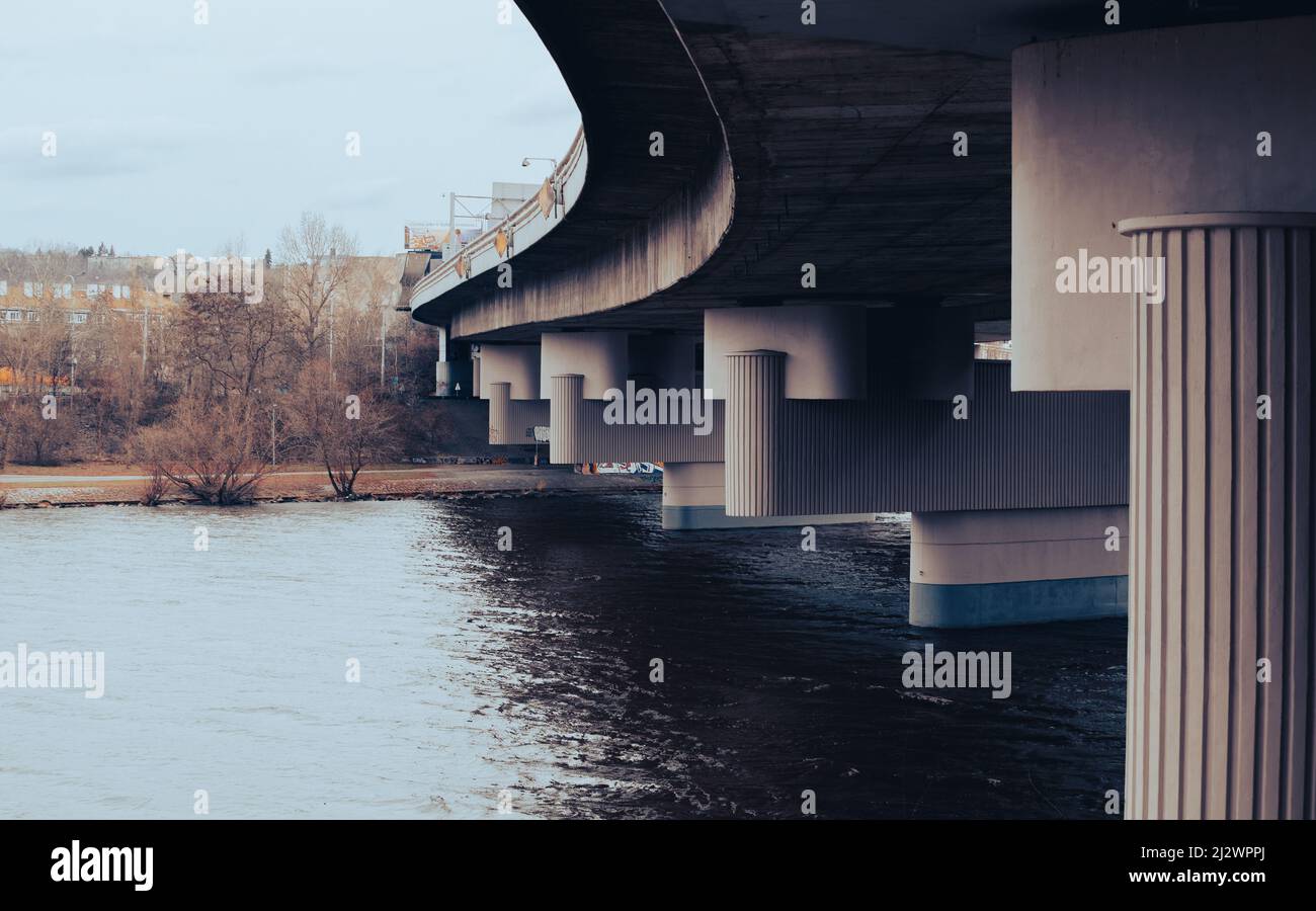 A concrete bridge viewed from below. The bridge turns to the left, the ...