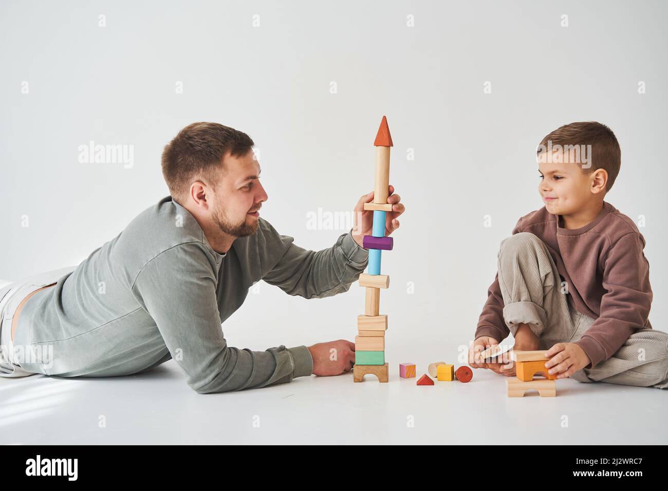 Caring dad helps his son to play on the floor on white background ...