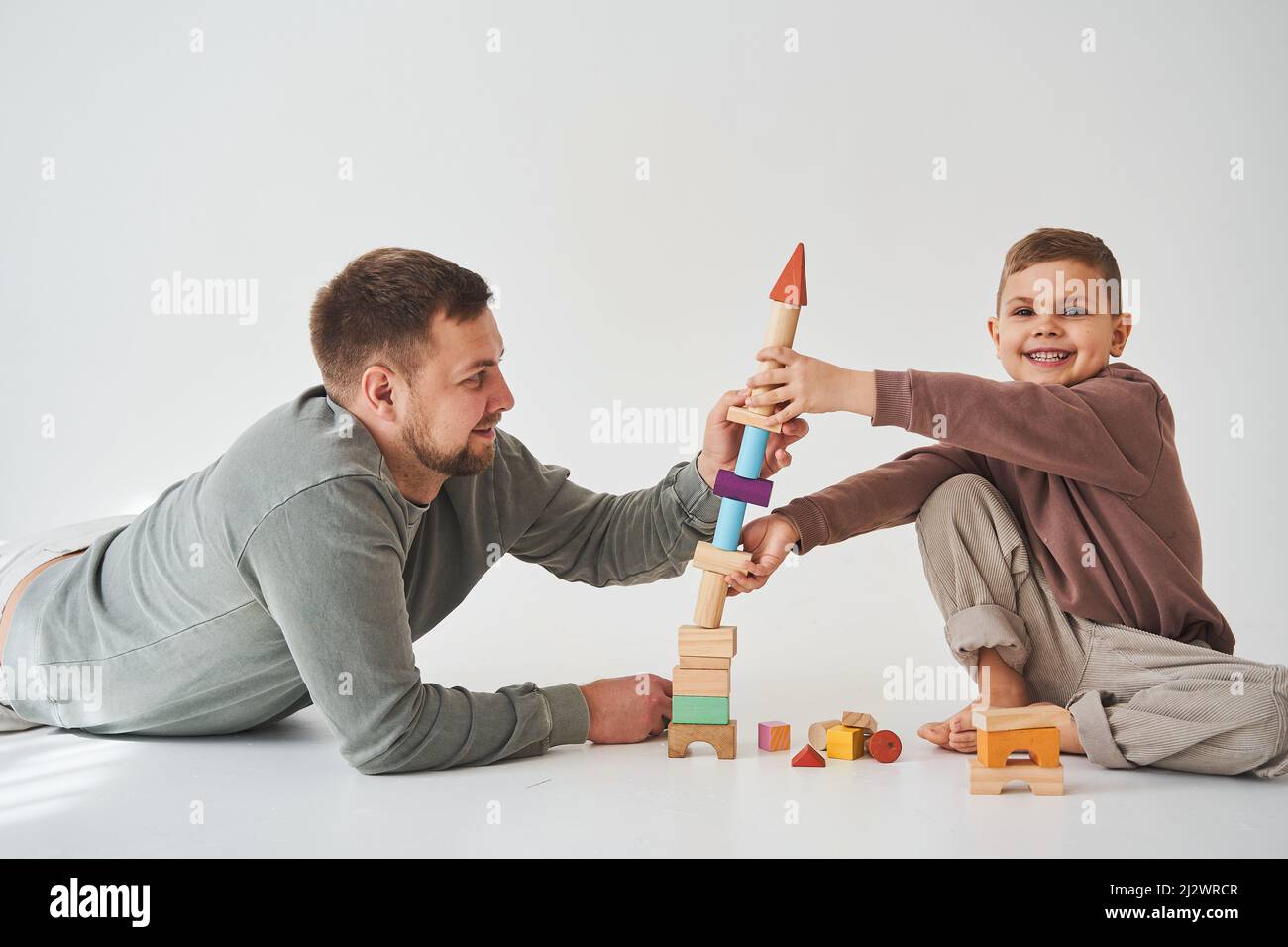 Caring dad helps his son to play on the floor on white background ...