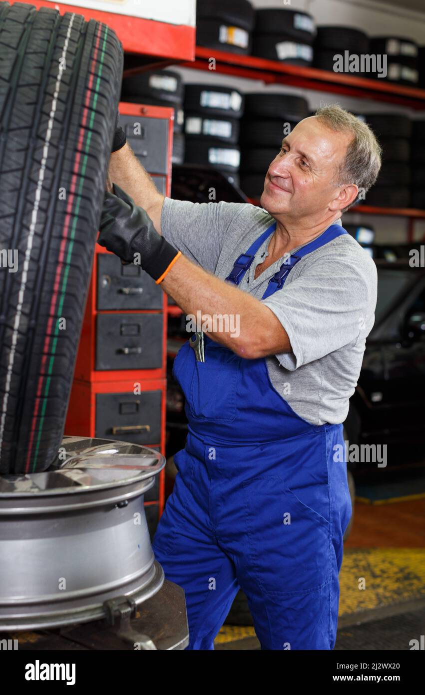 Qualified mechanic of service station straightening rim and repairing ...