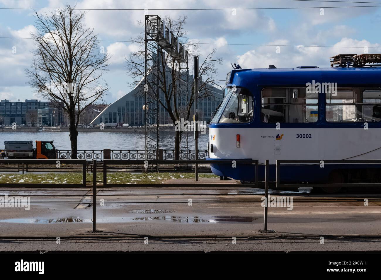 Tram with blue and white colors in front of river Daugava in Riga ...