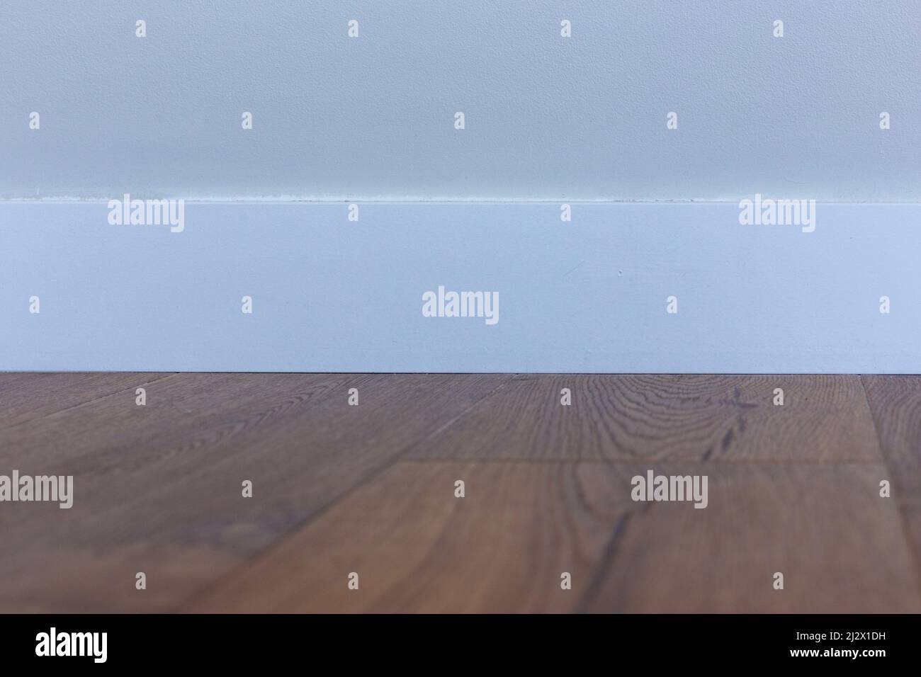 White baseboard, white wall and wood laminate Stock Photo - Alamy
